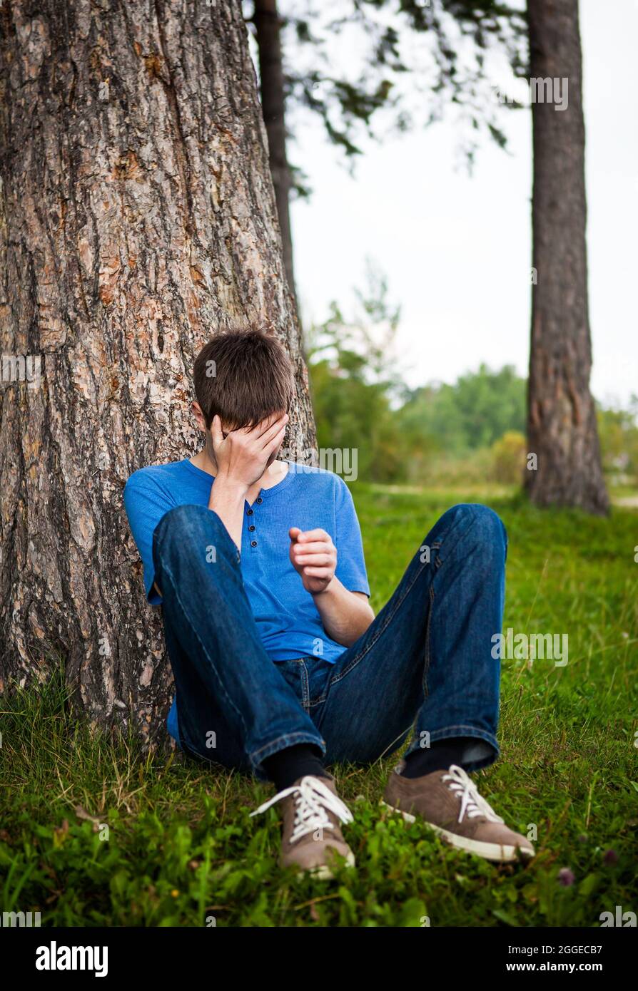 Sad Young Man sit under the Tree in the Park Stock Photo - Alamy