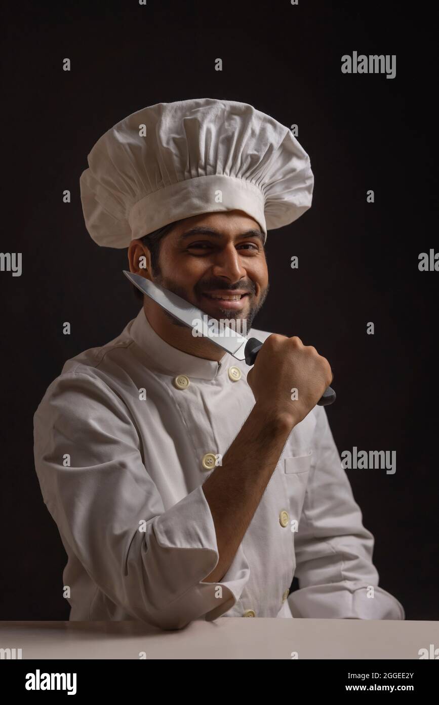 A HAPPY PROFESSIONAL CHEF SITTING AND POSING IN FRONT OF CAMERA Stock ...