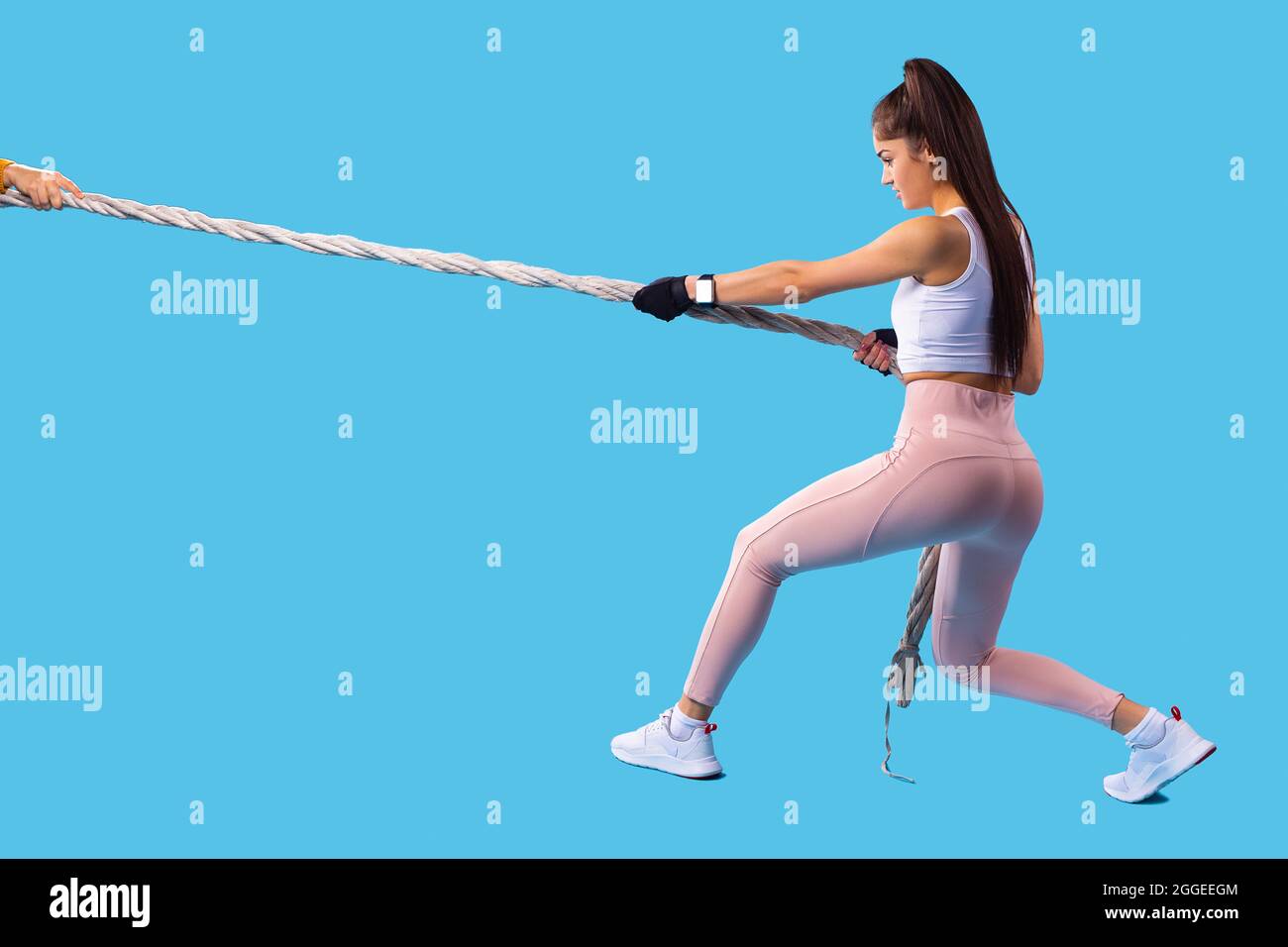 Strong muscled woman posing with the sport rope and making exercises ...