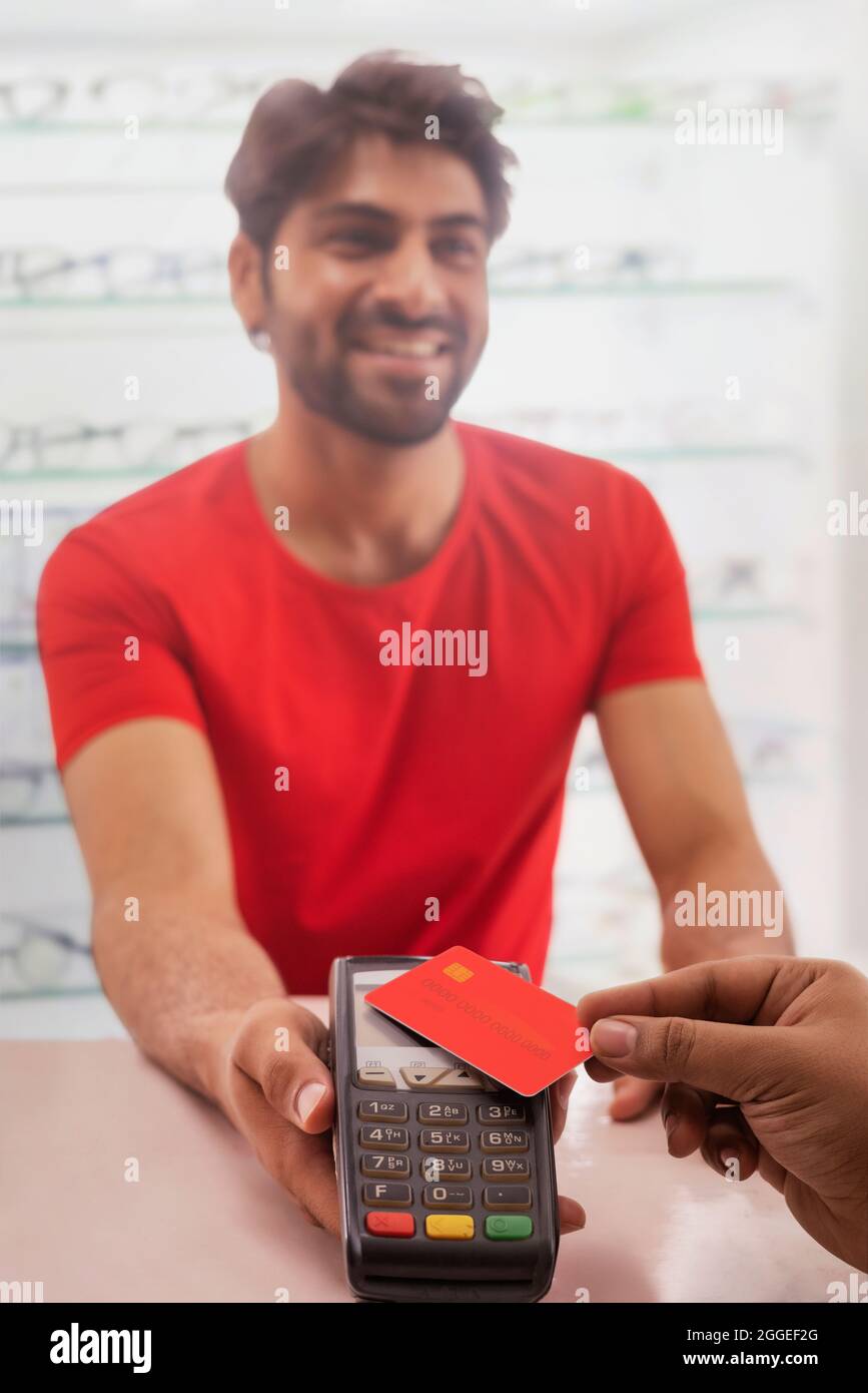 A CHEERFUL YOUNG MAN SHOWING CARD MACHINE TO PAY BILL Stock Photo - Alamy