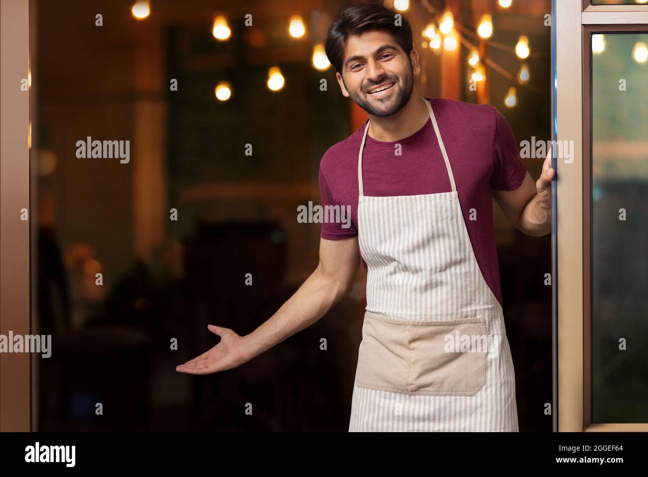 A HAPPY WAITER STANDING IN FRONT OF RESTAURANT AND WELCOMING Stock ...