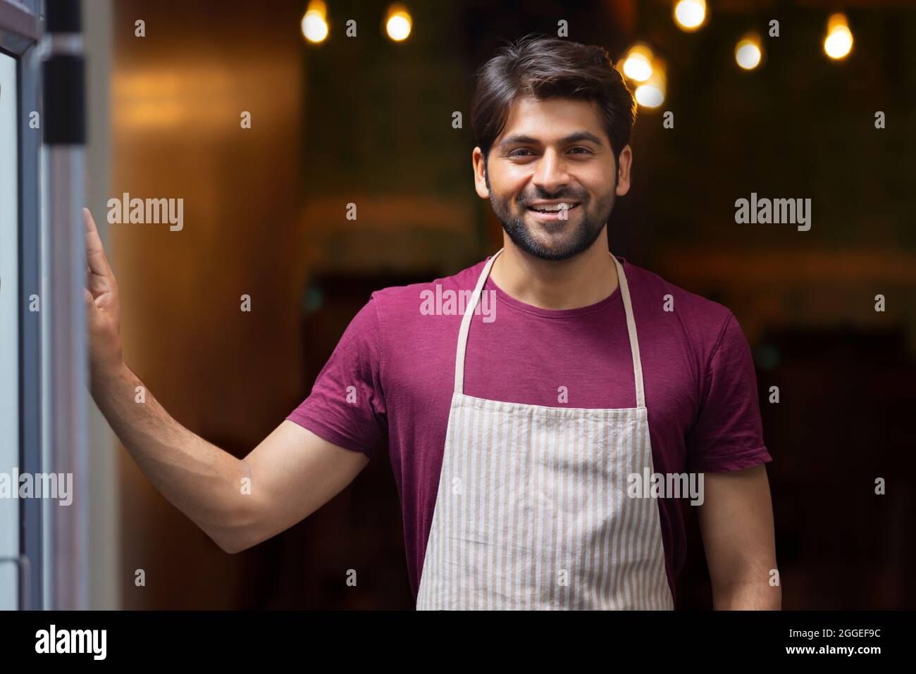 A CHEERFUL WAITER LOOKING AT CAMERA AND POSING WHILE IN RESTAURANT ...