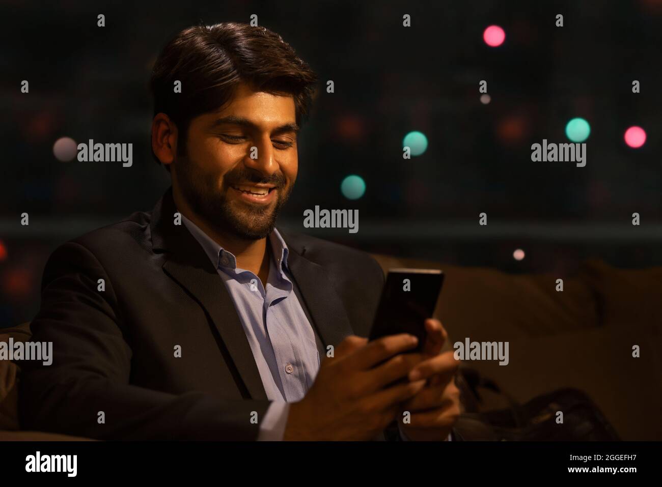 A YOUNG PROFESSIONAL HAPPILY USING MOBILE PHONE AT HOME Stock Photo - Alamy