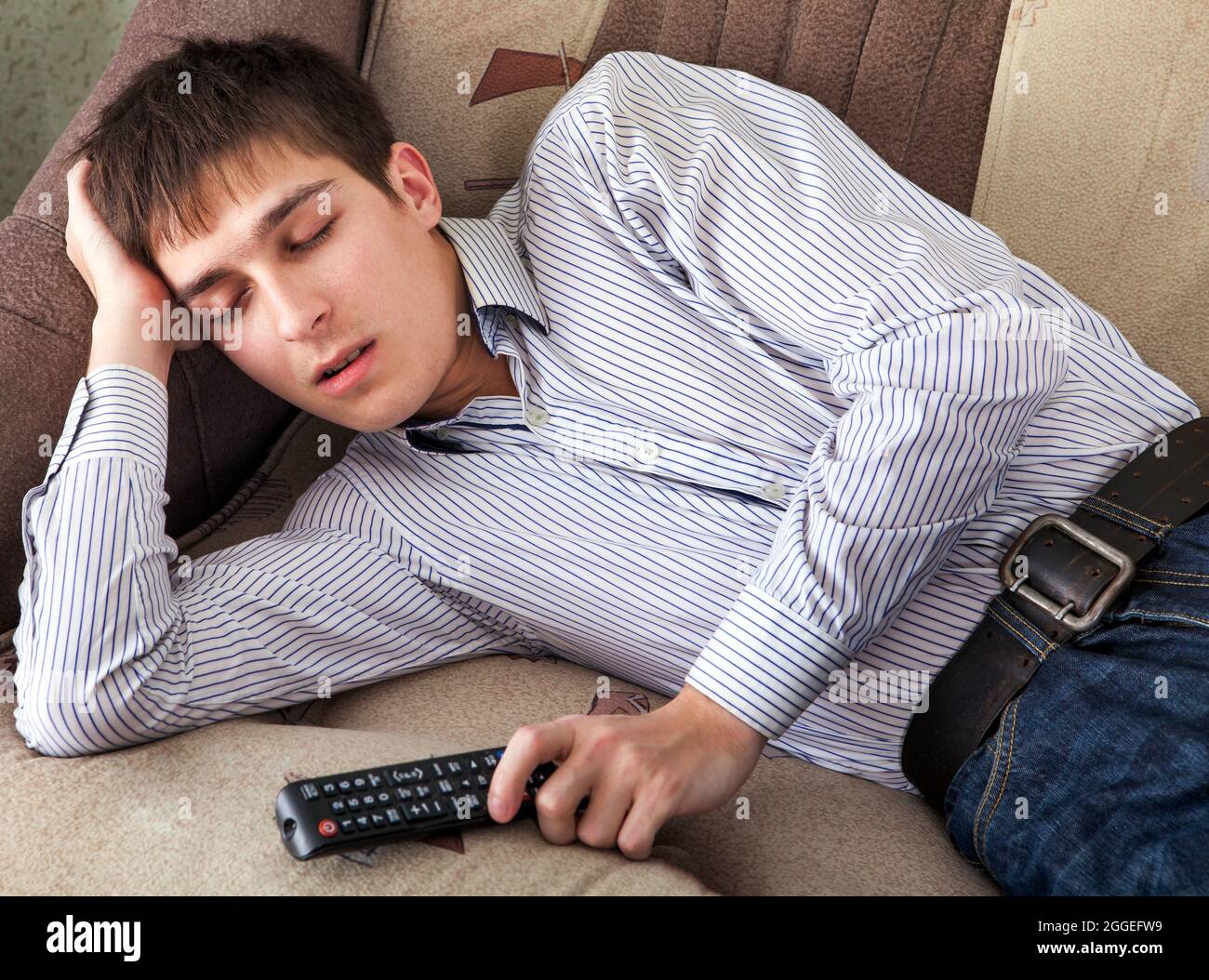 Tired Young Man sleep with TV Remote Control on the Sofa at the Home ...
