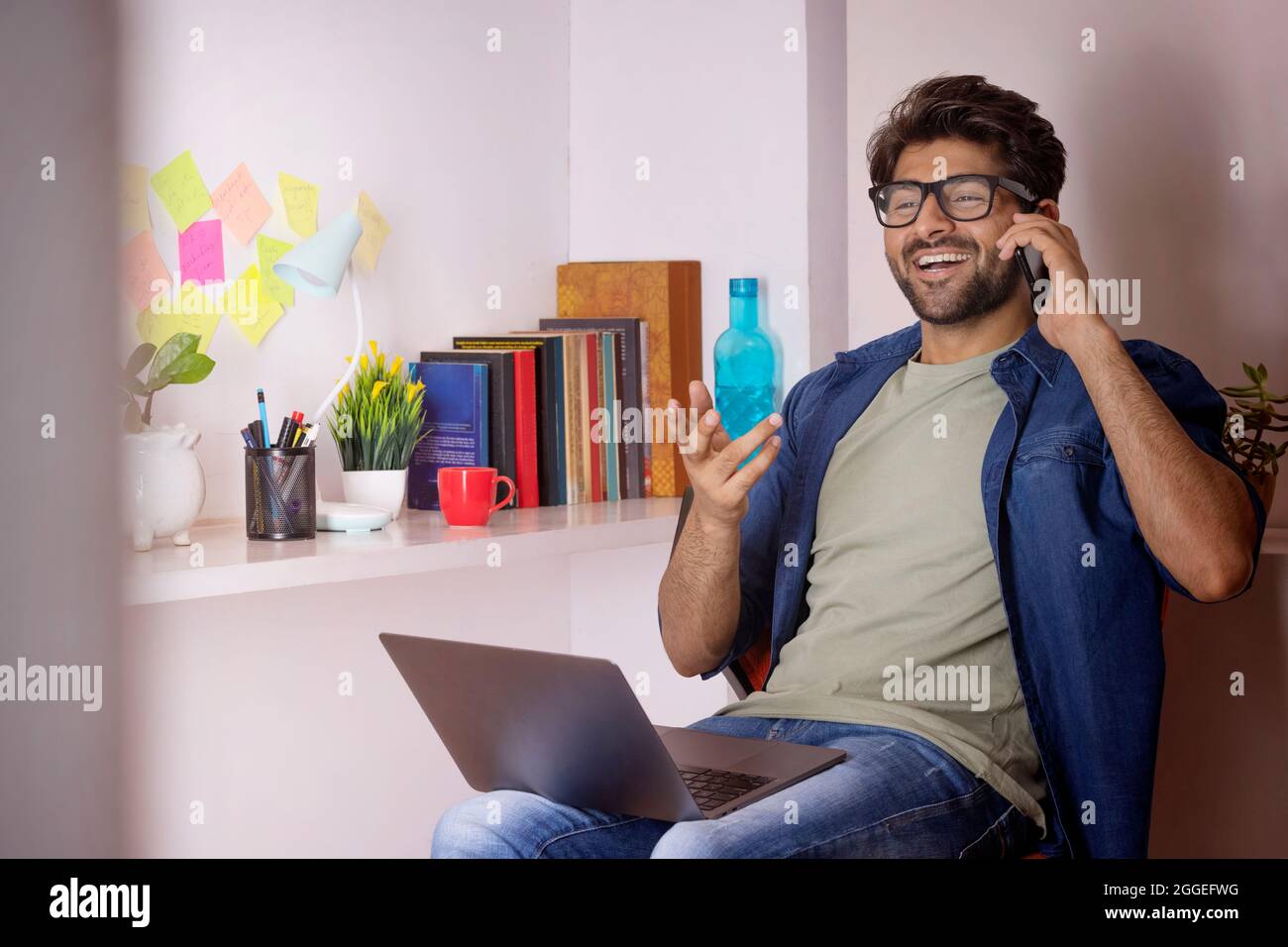 A YOUNG MAN HAPPILY TALKING OVER MOBILE PHONE WHILE WORKING Stock Photo ...