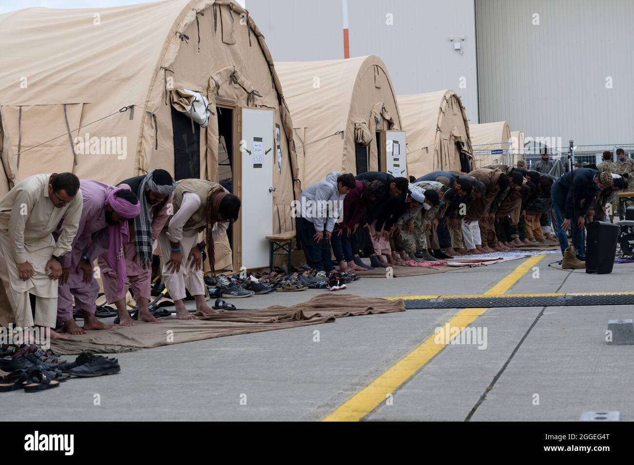 Evacuees bow during an Islamic ritual during Operation Allies Refuge ...
