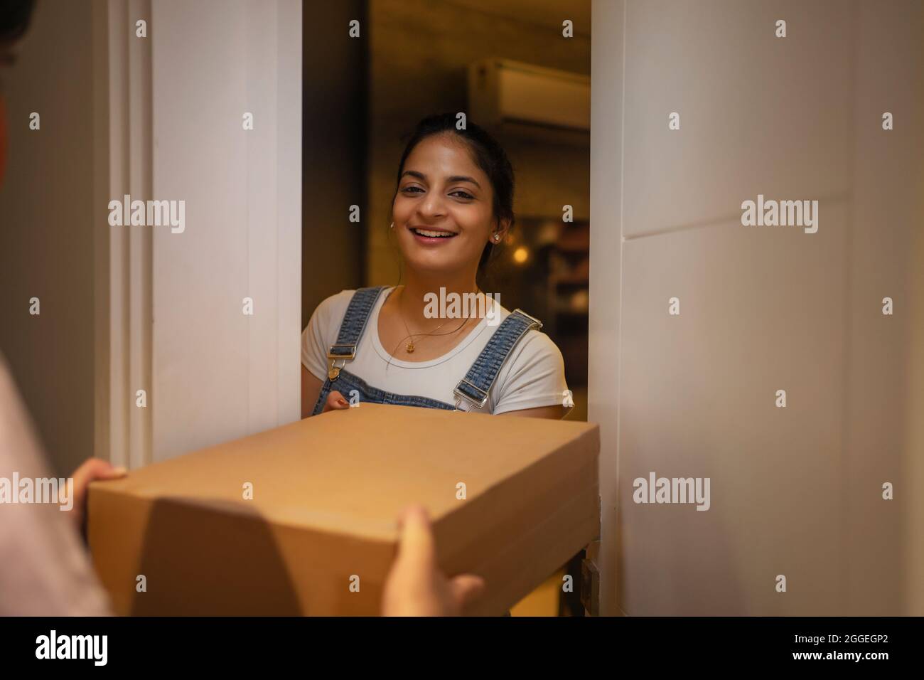 Young woman accepting delivery package at the doorstep Stock Photo - Alamy