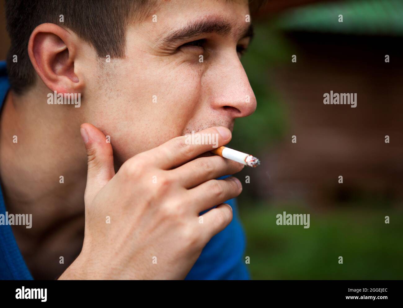 Sad Young Man smoking Cigarette outdoor closeup Stock Photo - Alamy