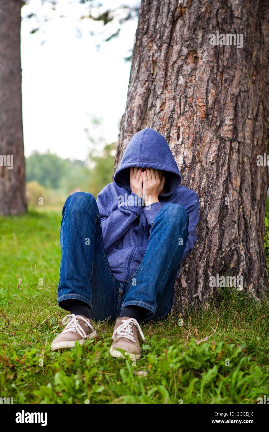 Sad Young Man sit under the Tree in the Park Stock Photo - Alamy