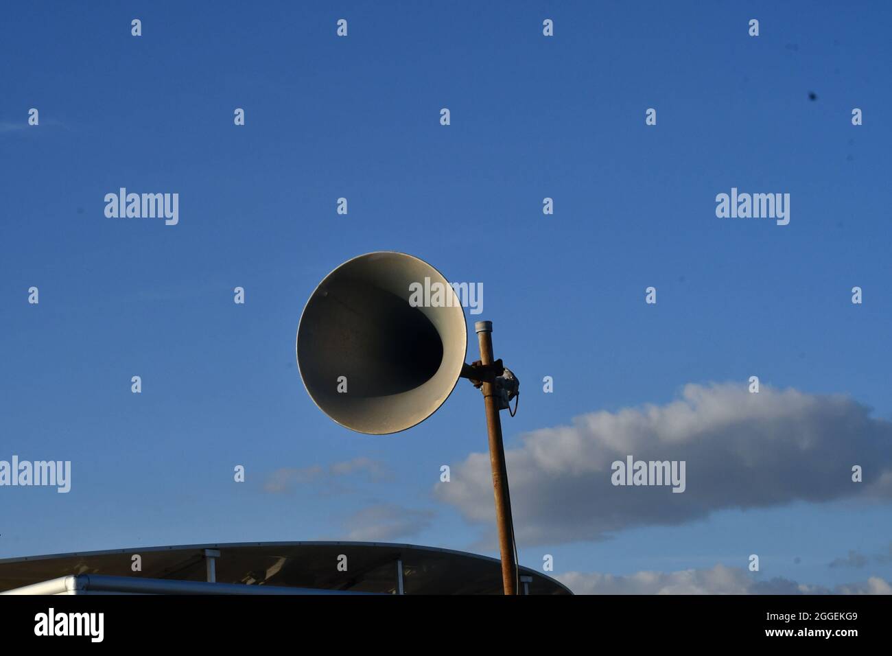 An old, retro style megaphone with the backdrop of a blue sky with ...