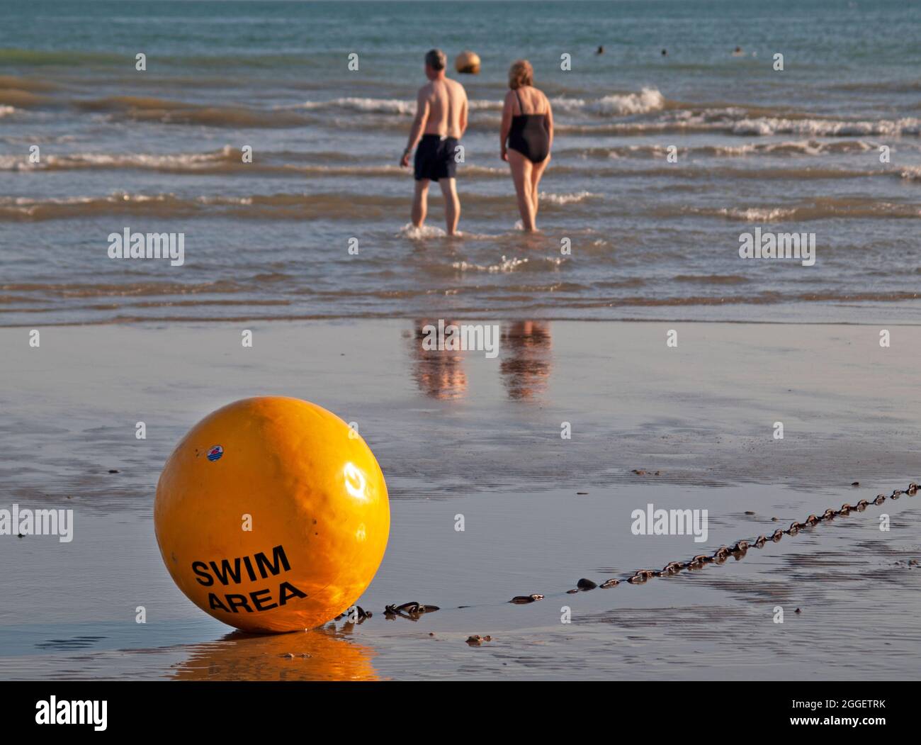 A couple walk into the sea for a swim at Brighton Stock Photo - Alamy