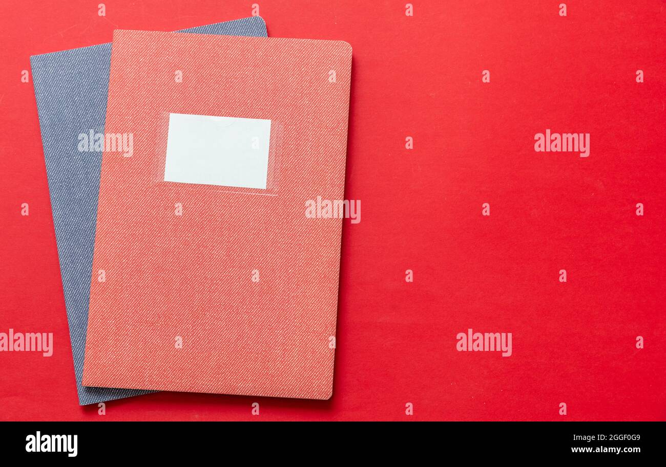 School notebooks blue and red color on red background, blank label ...