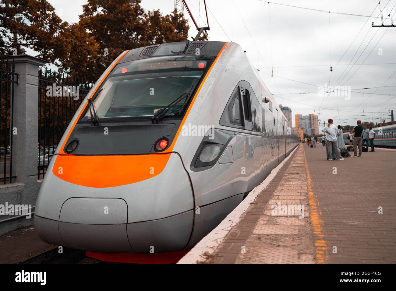 High speed orange train at the train station at sunset. Modern ...