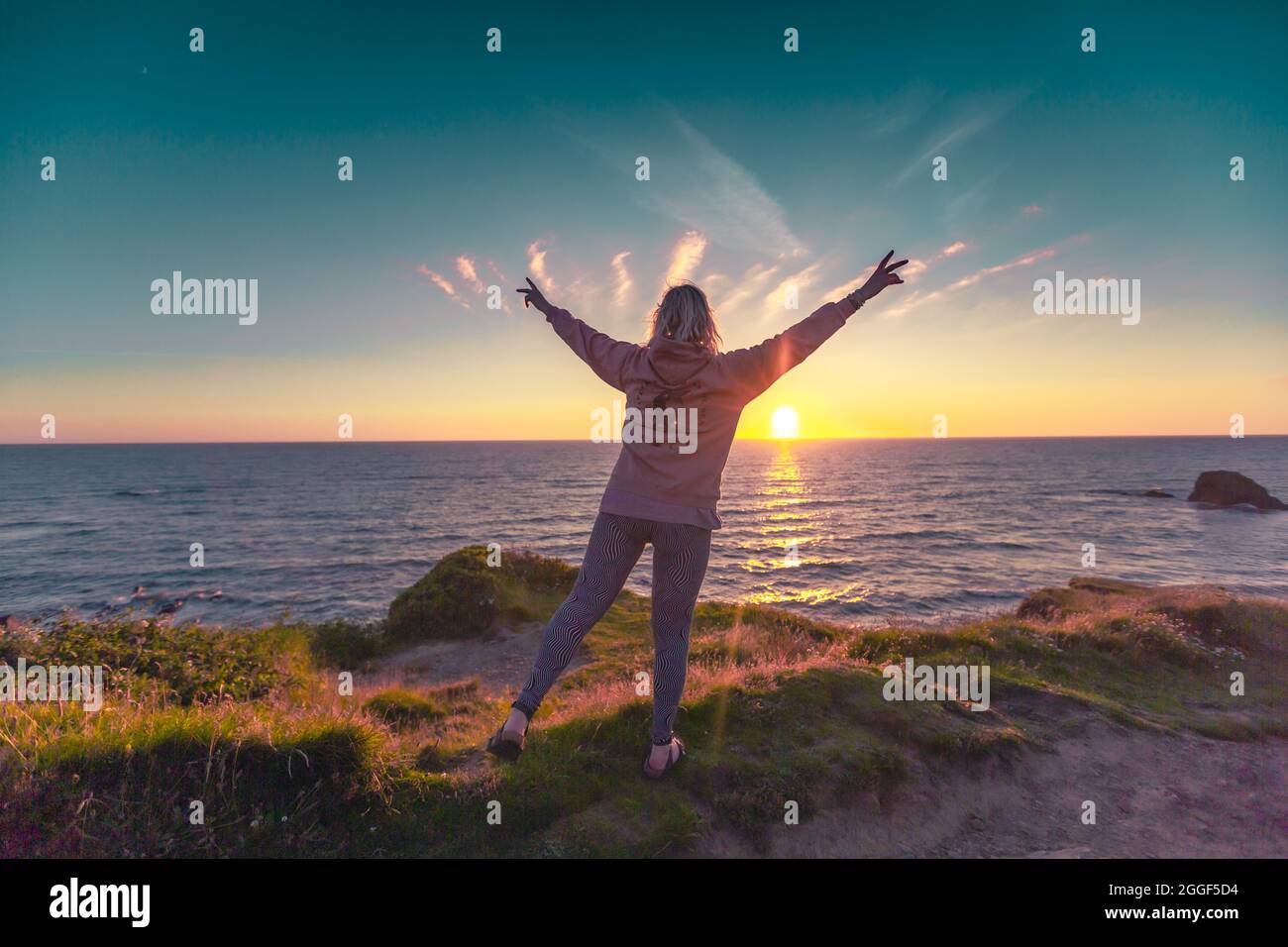 Female trying to embrace the sun at sunset near the beach Stock Photo ...