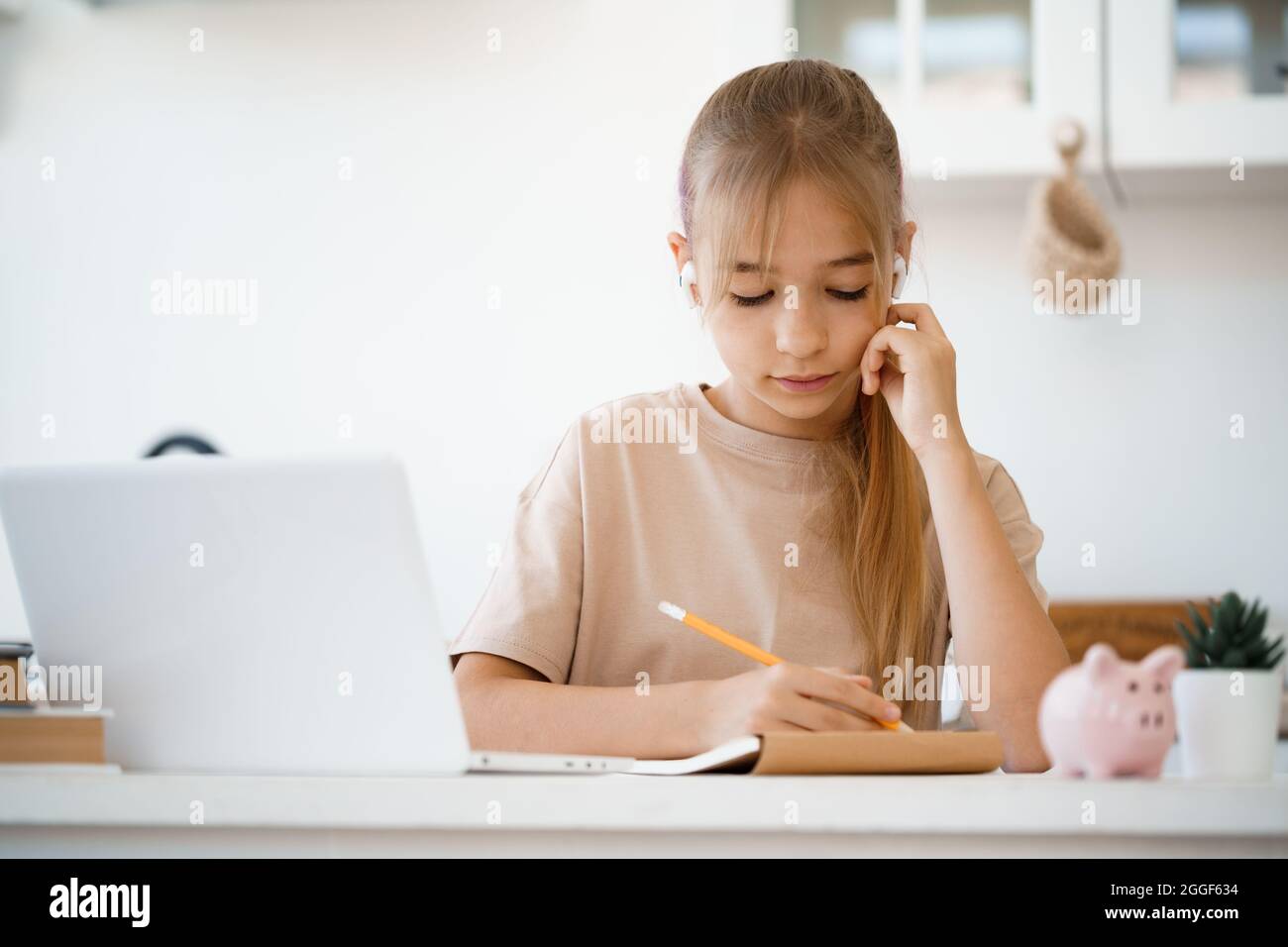 Teenage girl making notes in notepad, doing homework at table at home ...