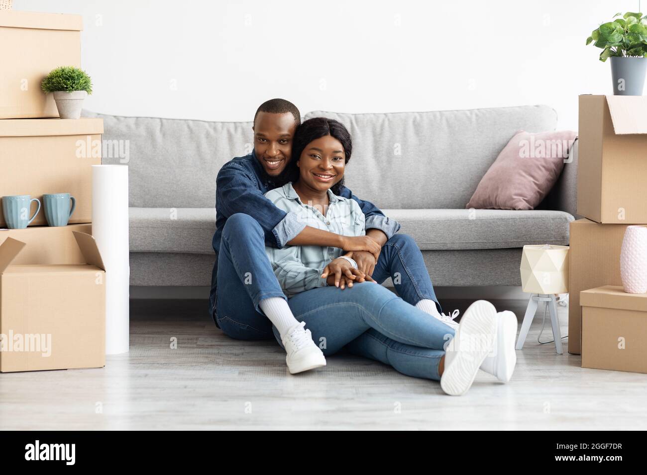 Happy african american couple sitting on floor in room with cardboard ...