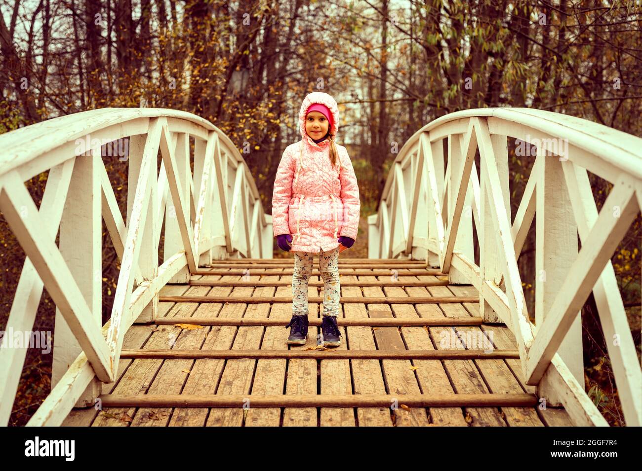 little happy six year old kid girl in autumn clothes stands on the ...