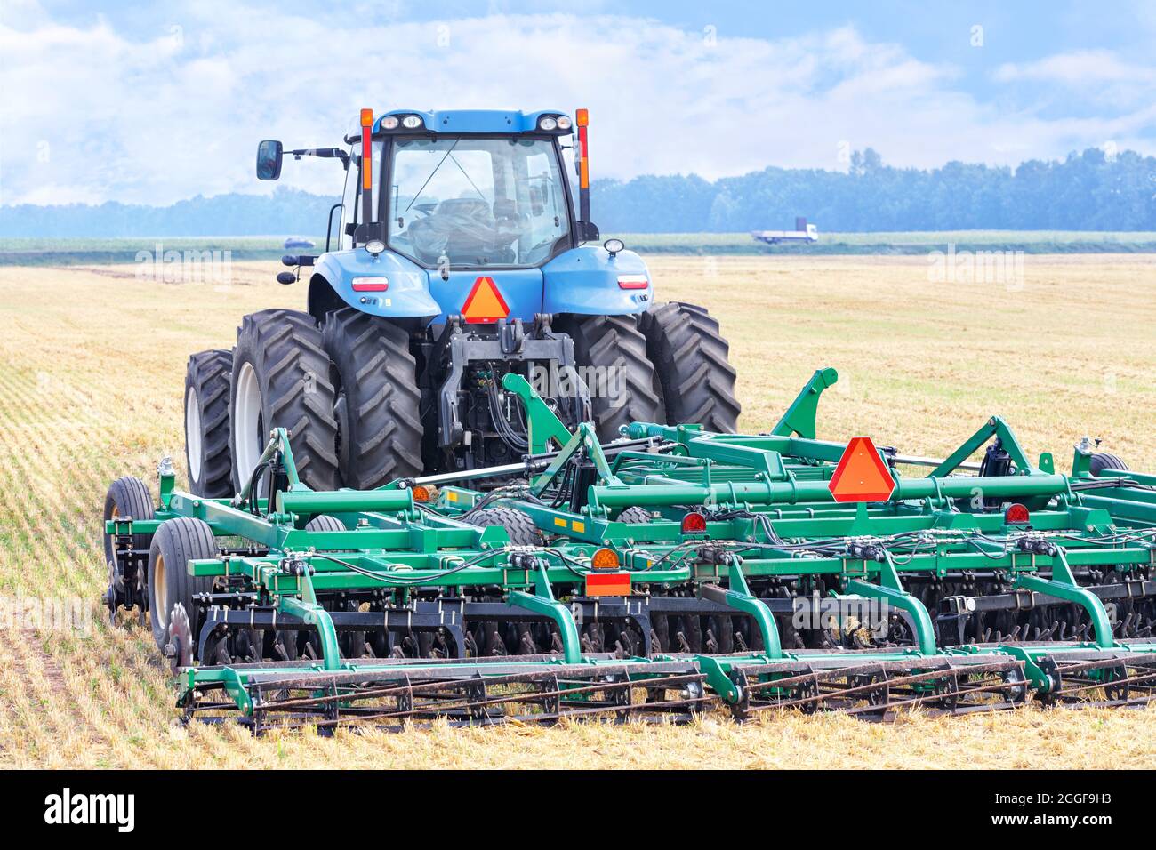 An agricultural tractor with a hitch, a harrow, stands against the ...