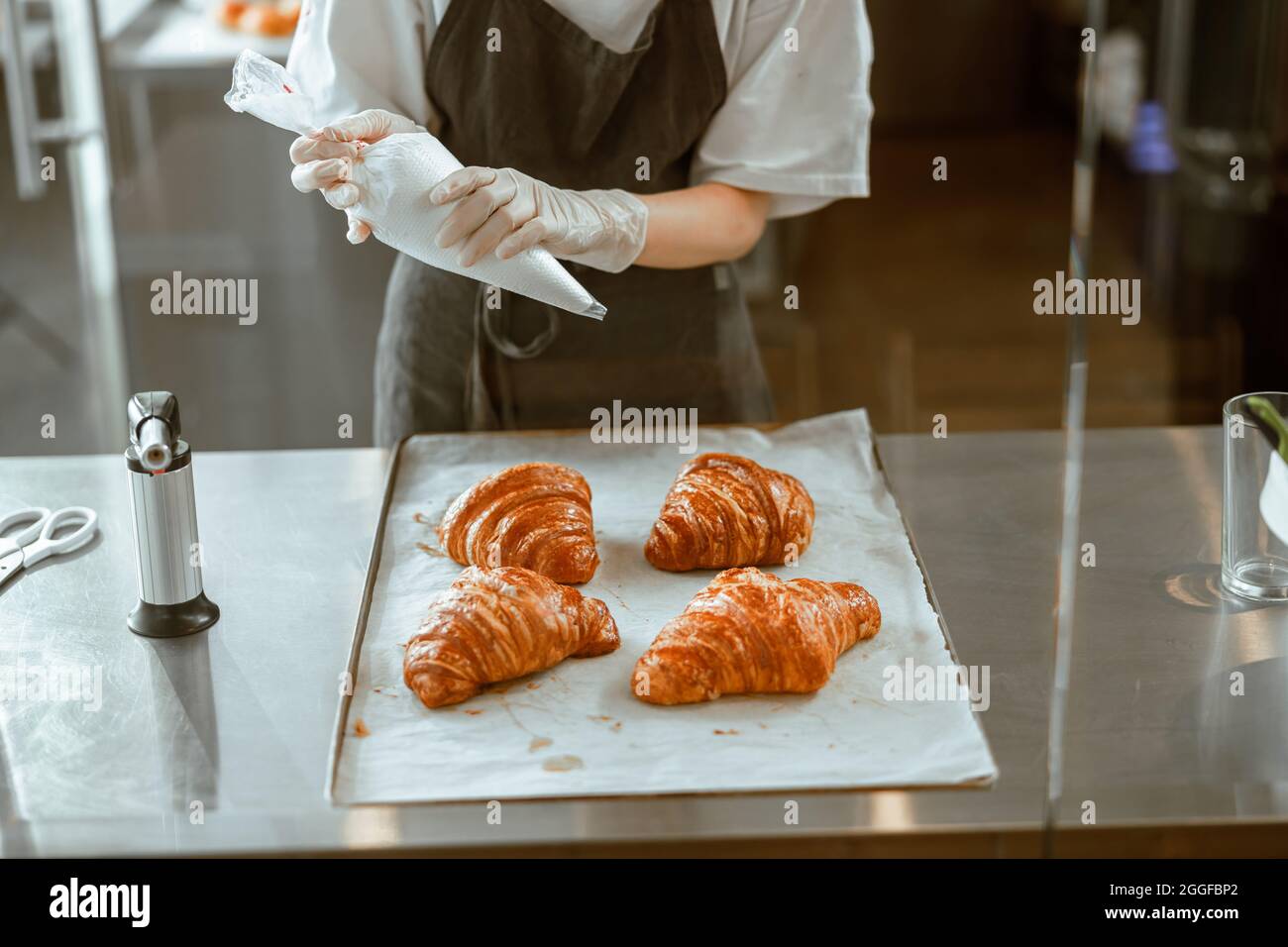 Employee holds confectioner sleeve with delicious cream to decorate ...