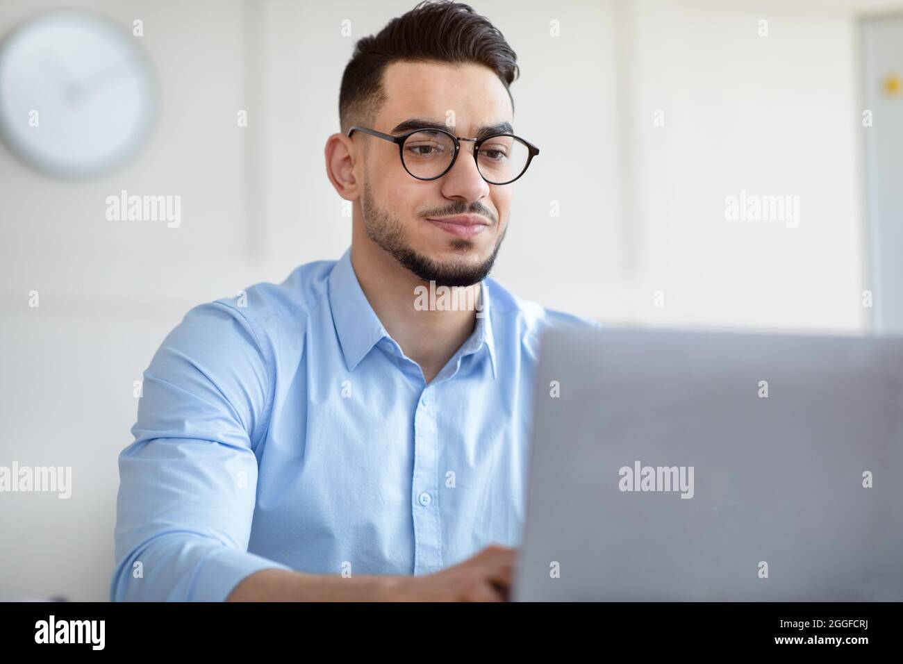 Remote work concept. Handsome Arab man using laptop pc, searching info ...