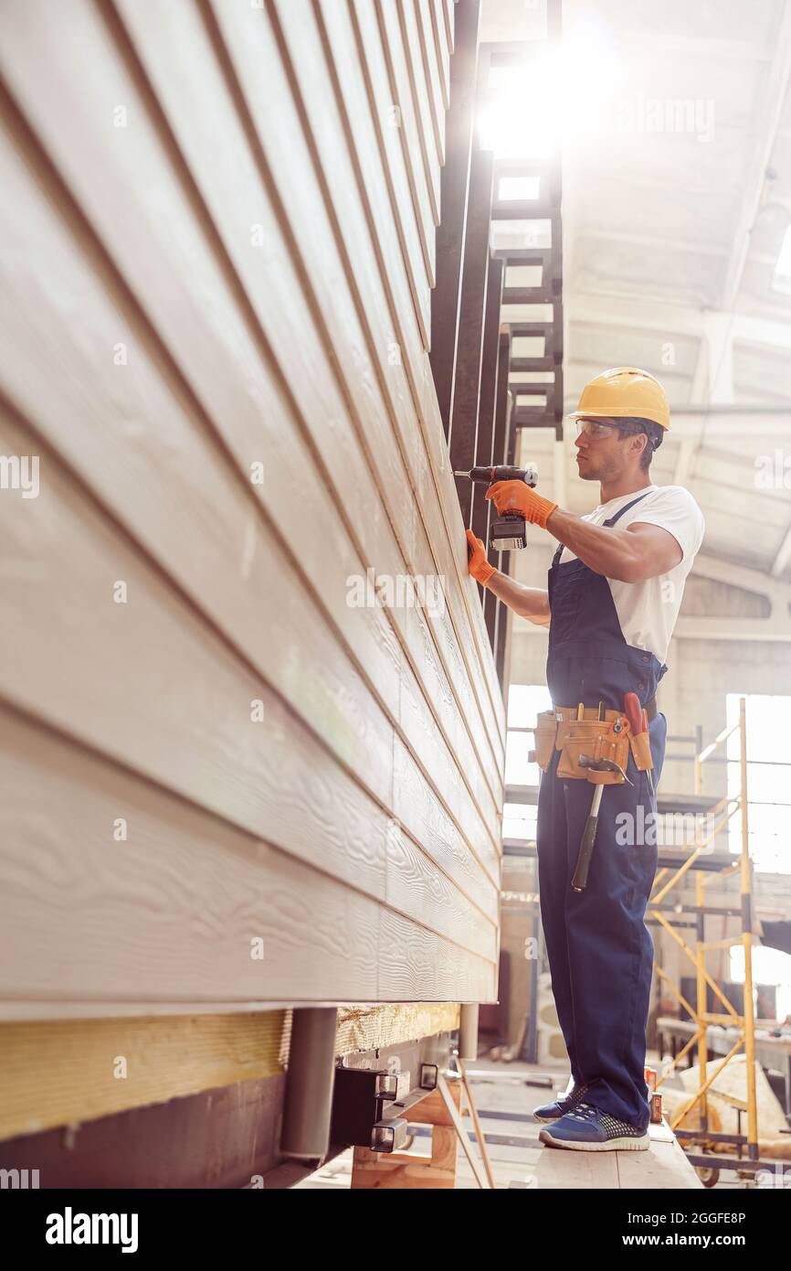Male builder using cordless electric drill at construction site Stock ...