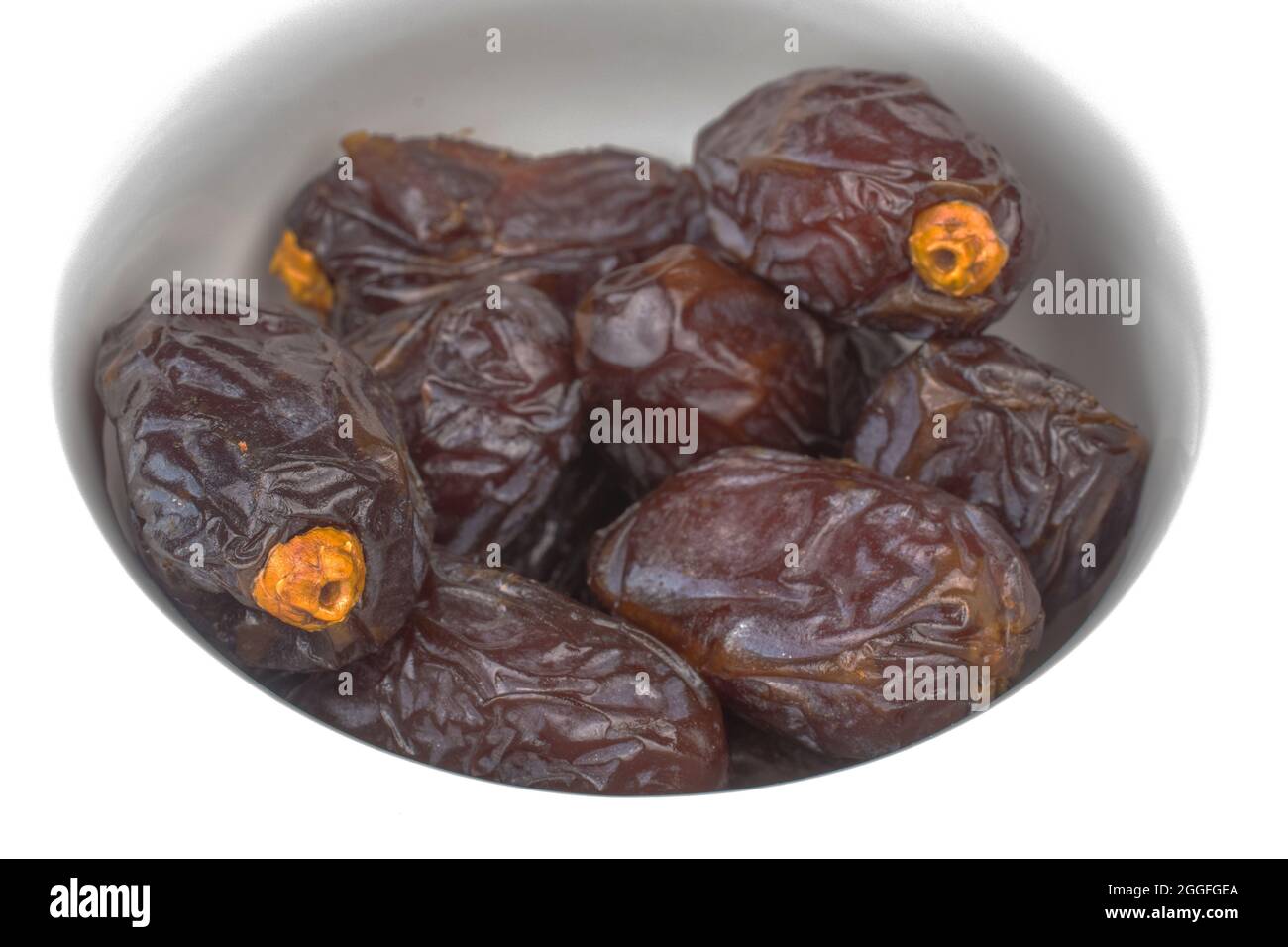 Several royal dates in a white ceramic dish, close-up, isolated on ...