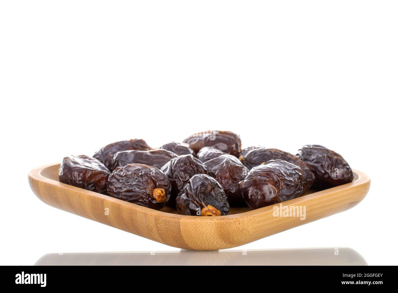 Several royal dates on a bamboo plate, close-up, isolated on white ...