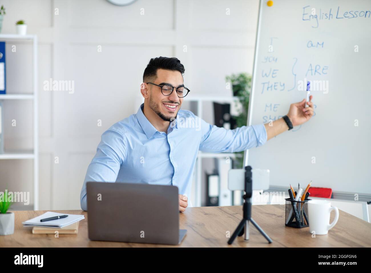 Cyberlearning, remote education concept. Happy Arab male teacher giving ...