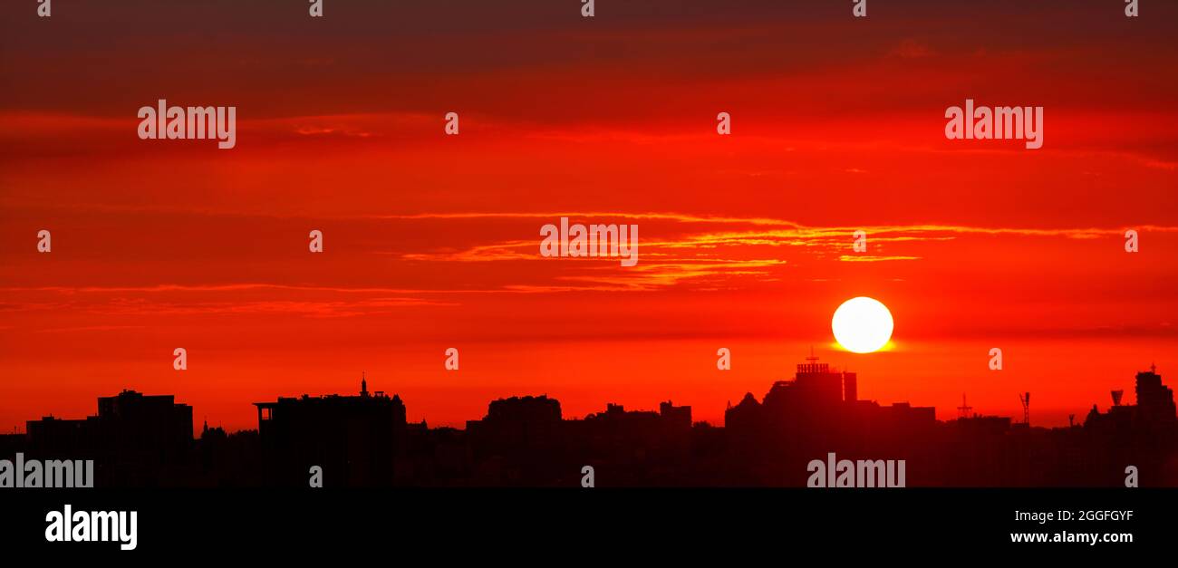 Black outline of the night city against the background of a bright red ...