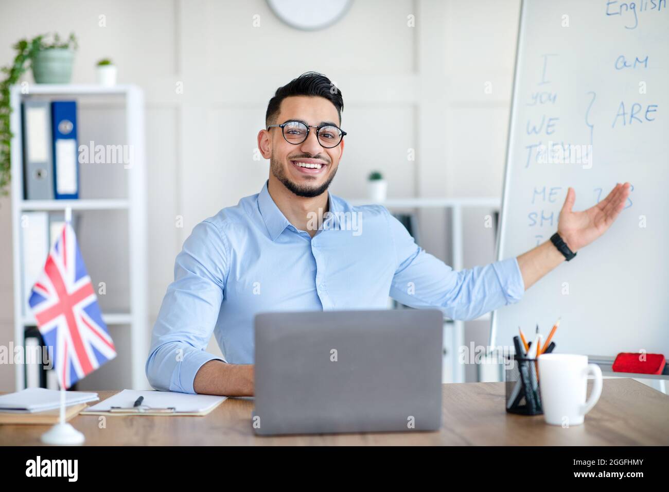 Young Arab tutor teaching British English online, giving foreign ...