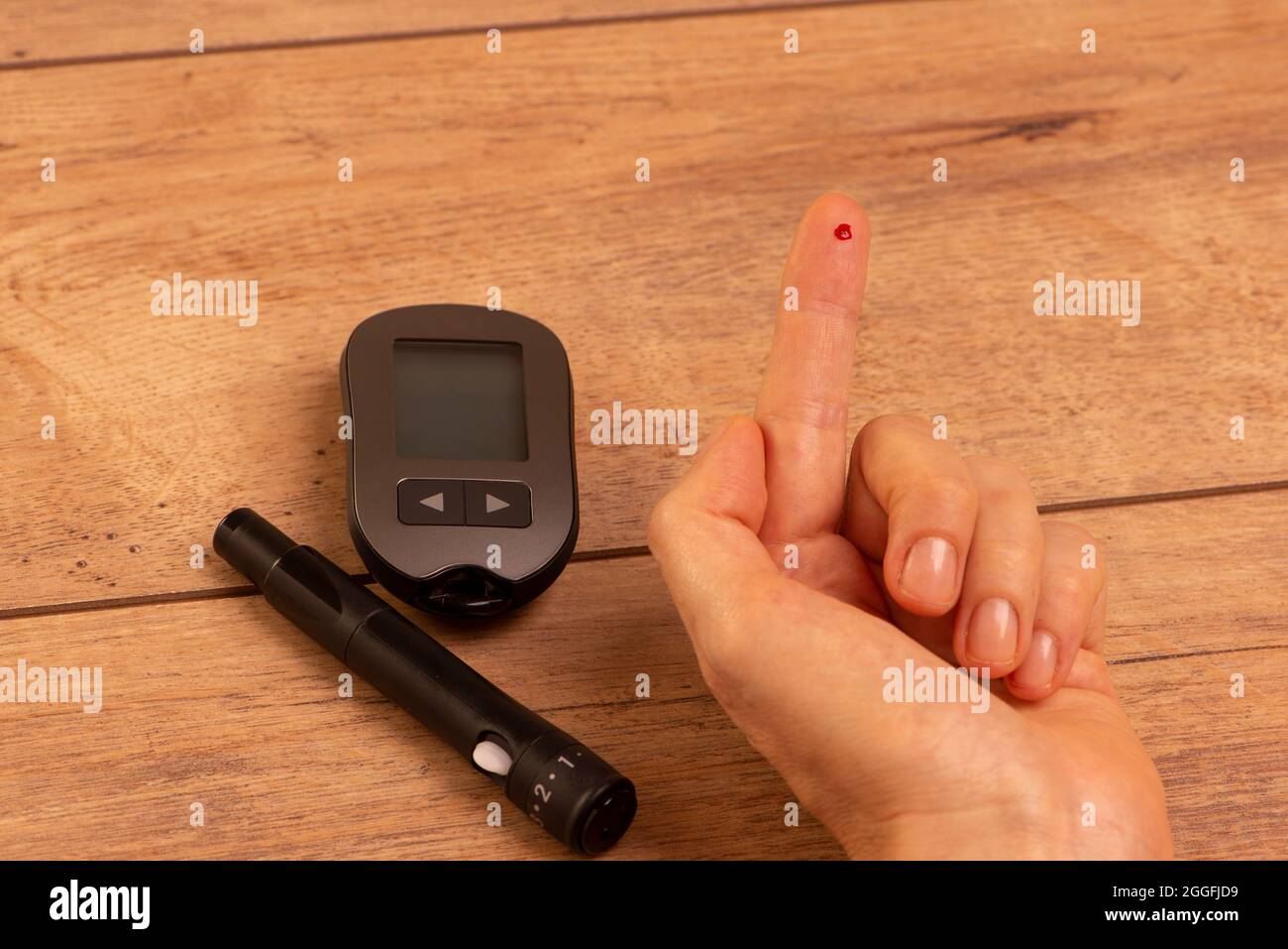 a drop of blood on a woman's finger to measure glucose using glucometer ...