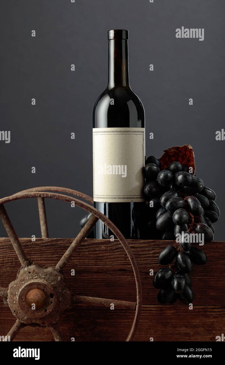 Old wooden cart on rusty iron wheels with bottle of red wine and grapes ...