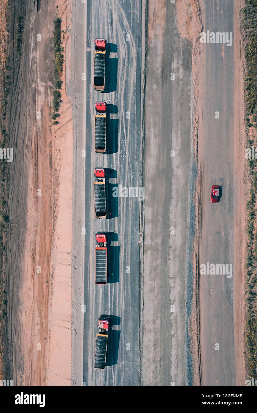 Convoy of trucks rides on asphalt road with one red car on another side ...