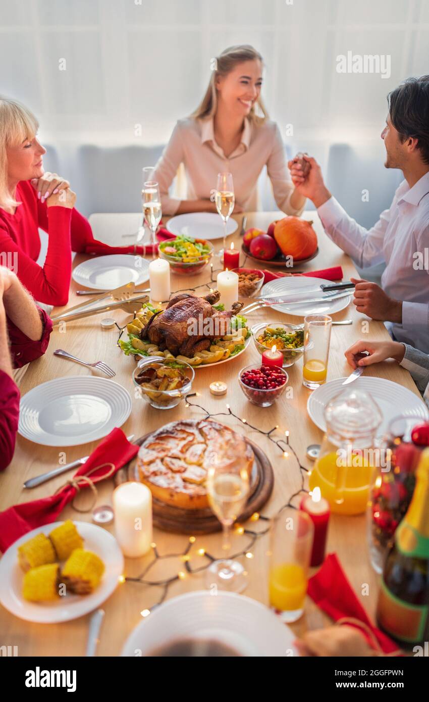 Cheerful extended family sitting at served table with holiday meal ...
