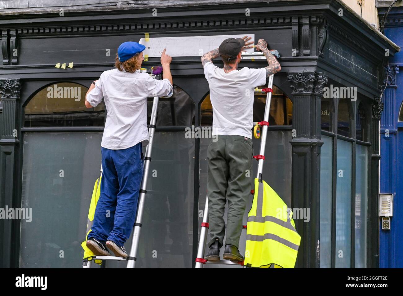 Bath, England - Two sign writers on ladders preparing to paint a sign ...