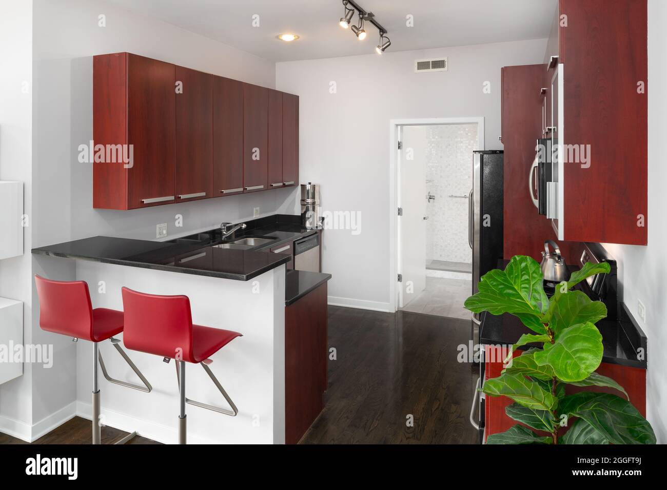 A kitchen with cherry red cabinets, red chairs sitting at a black ...
