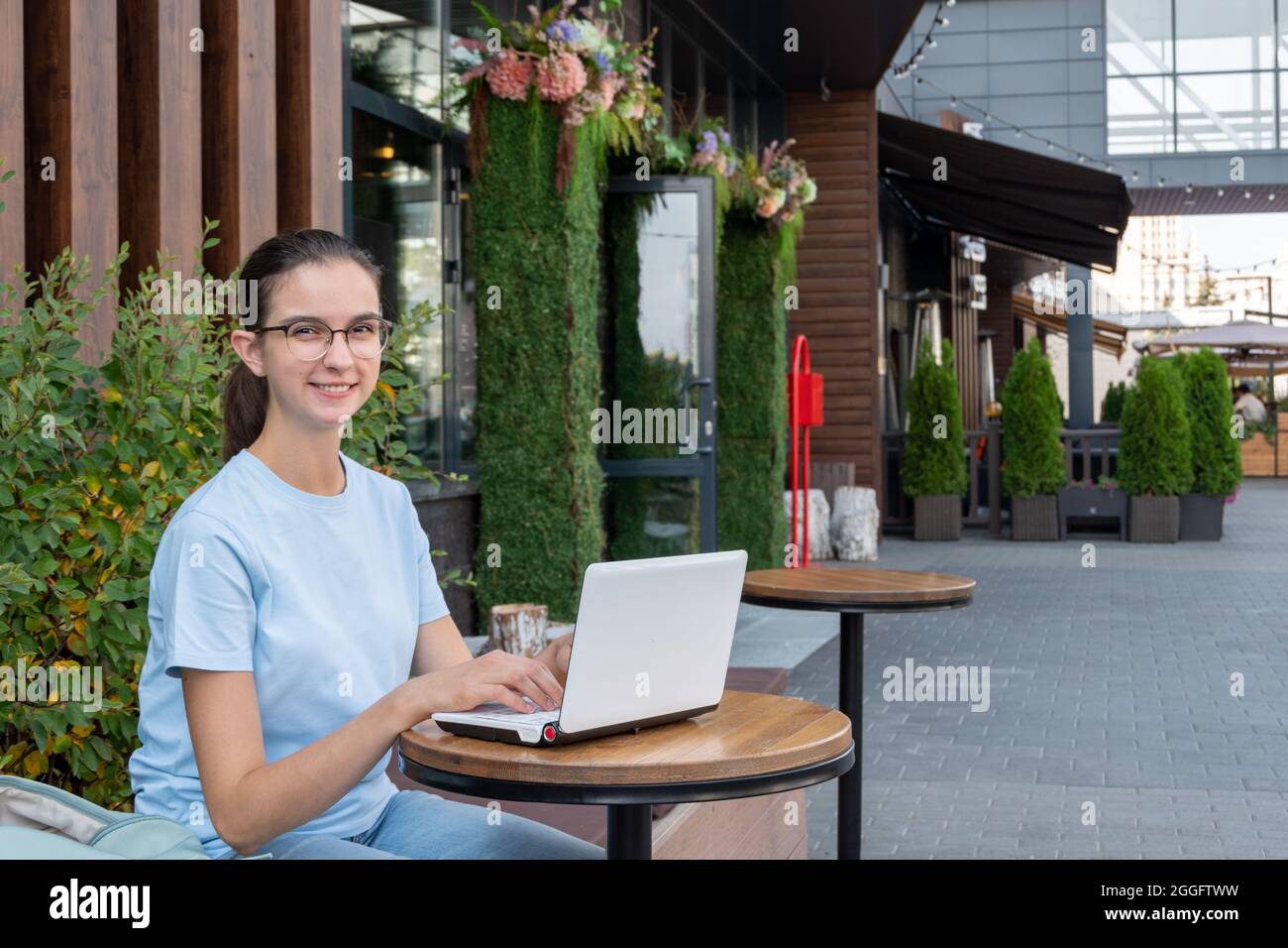 Happy woman using laptop in outdoor cafe, girl typing letter studying ...