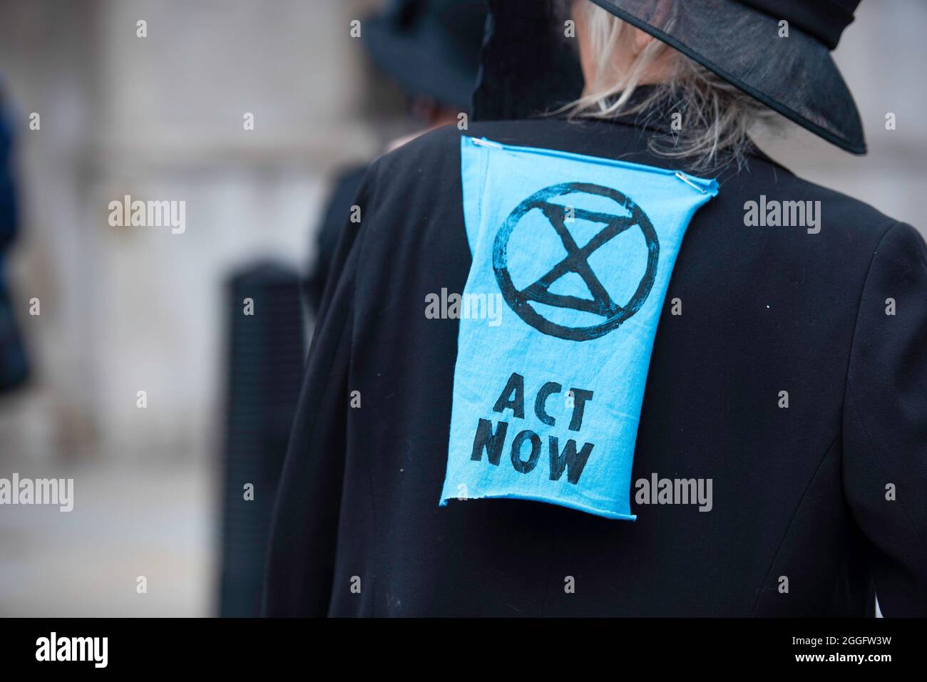 UK. 31st Aug, 2021. An activist wears an "Act Now" sign on her back ...