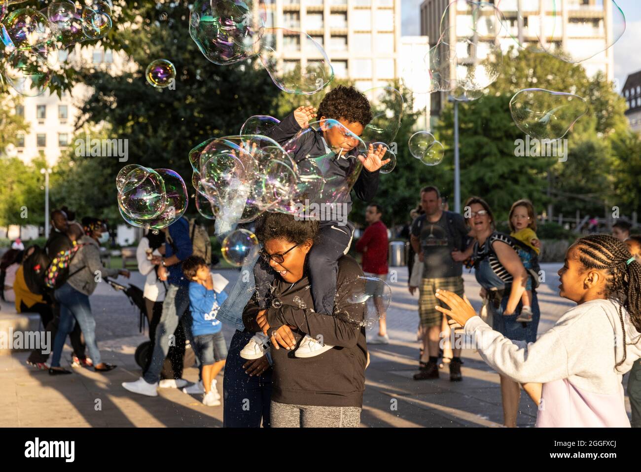 Families enjoy the street entertainment along the Southbank in London ...