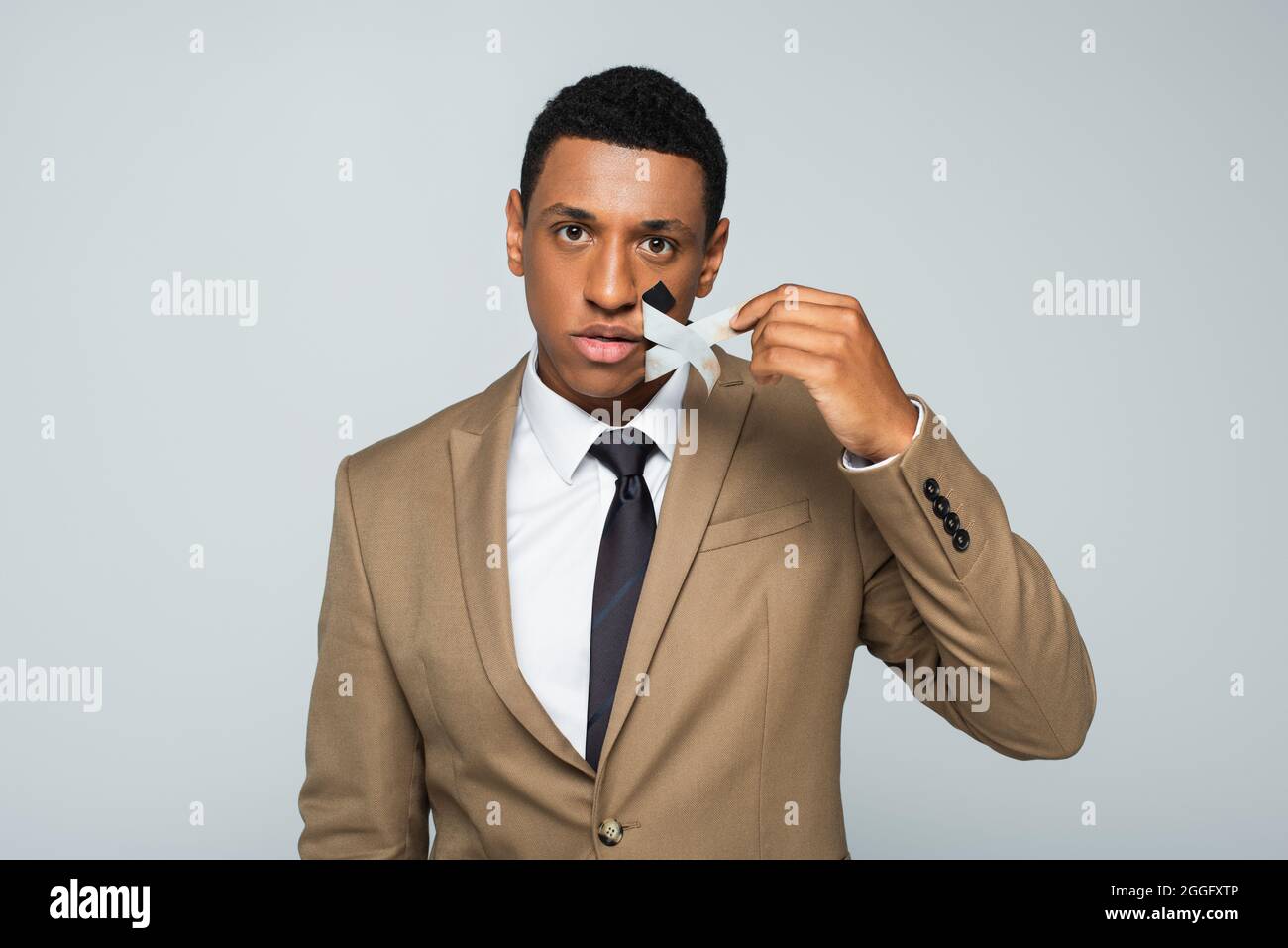 african american businessman taking off scotch tape on mouth isolated ...