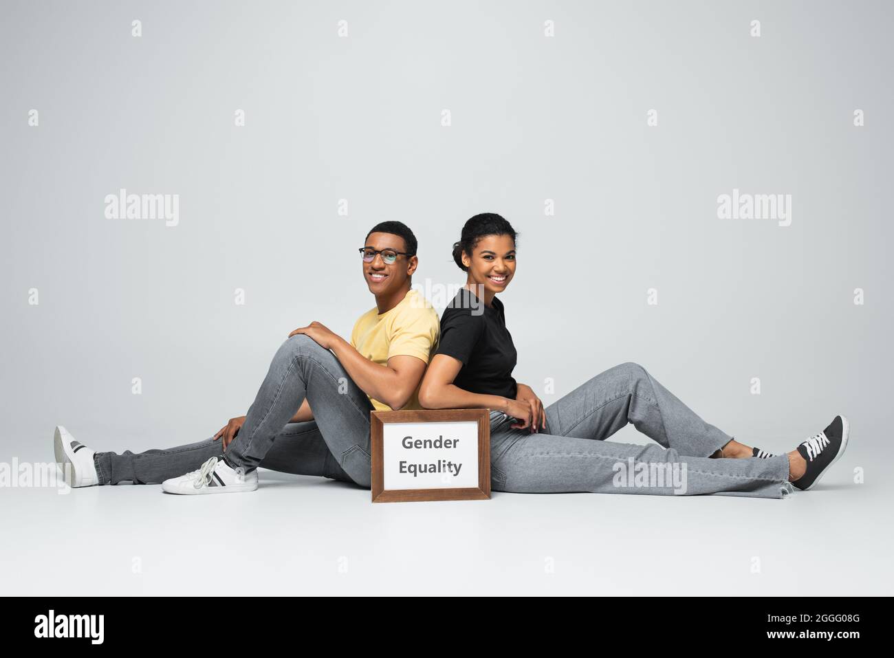 full length of happy african american man and woman sitting near ...