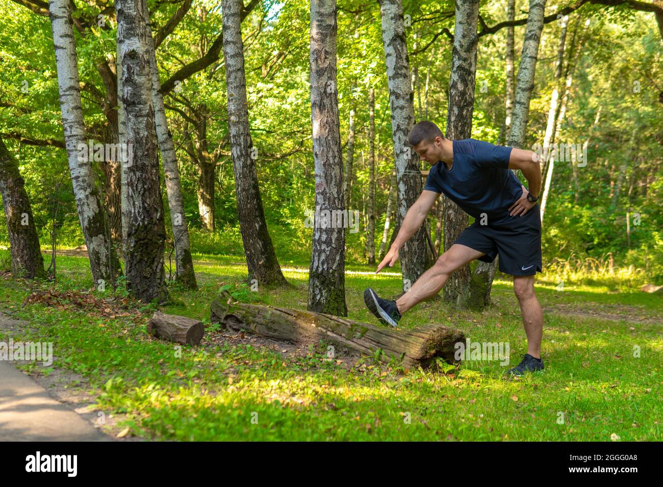 A young enduring athletic athlete is doing stretching in the forest ...