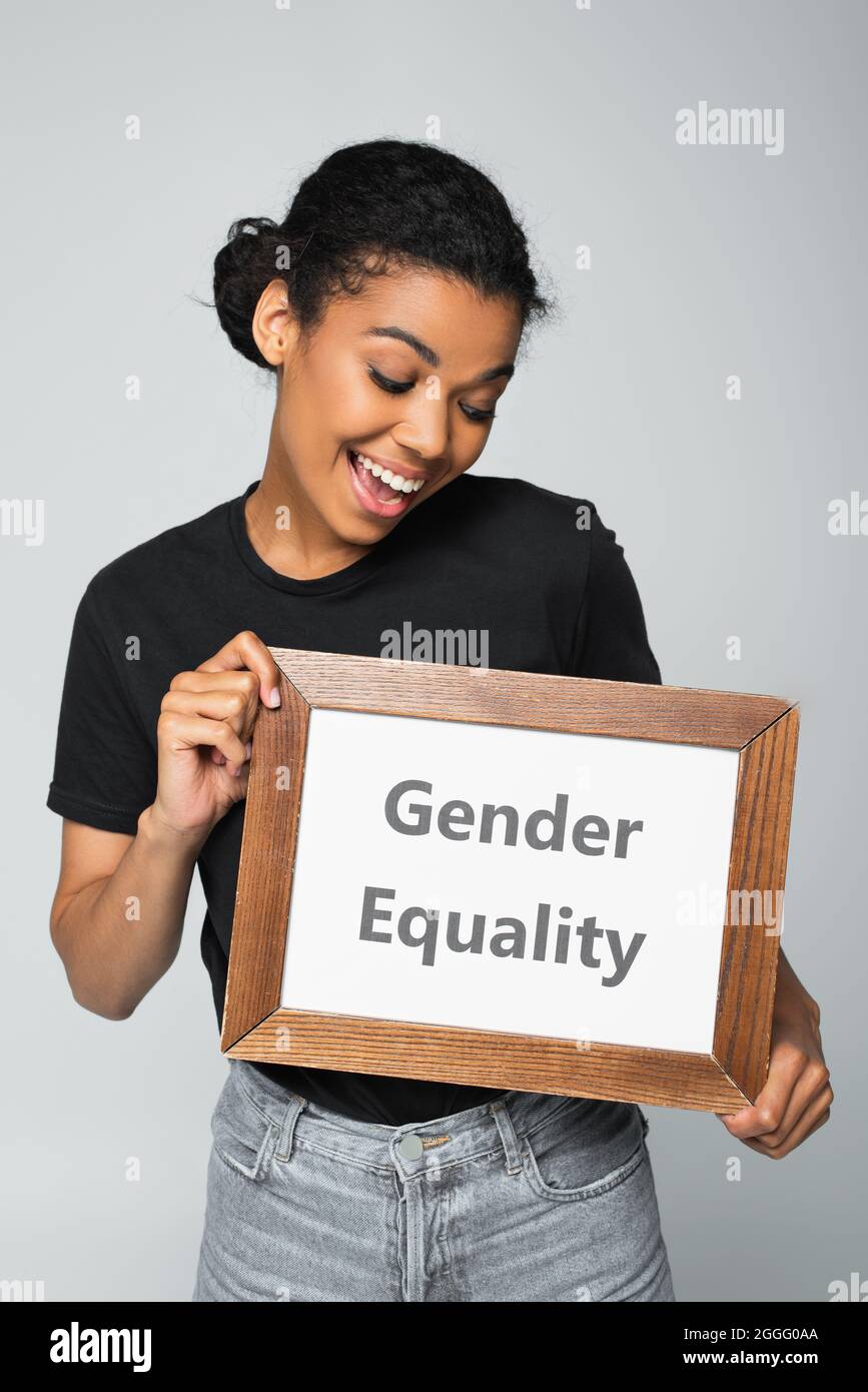amazed african american woman holding placard with gender equality ...