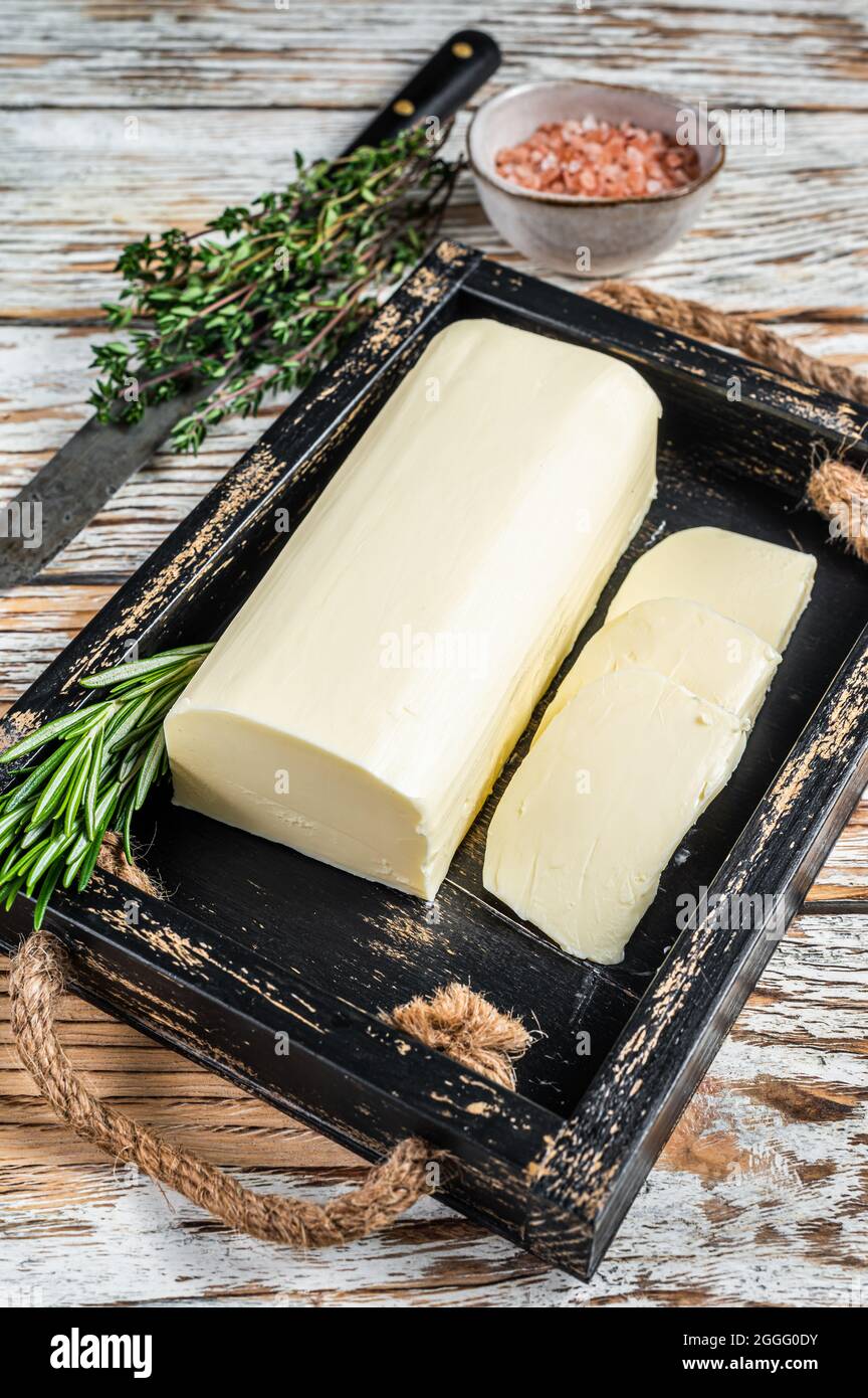 Butter Margarine block in a wooden tray with herbs. White wooden ...