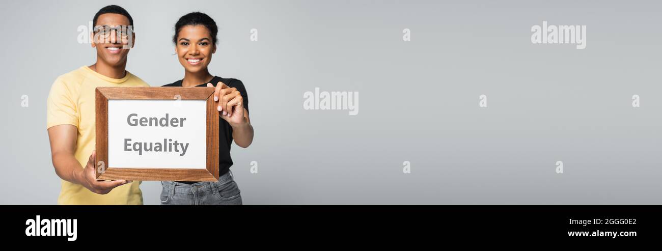blurred and happy african american man and woman holding wooden frame ...
