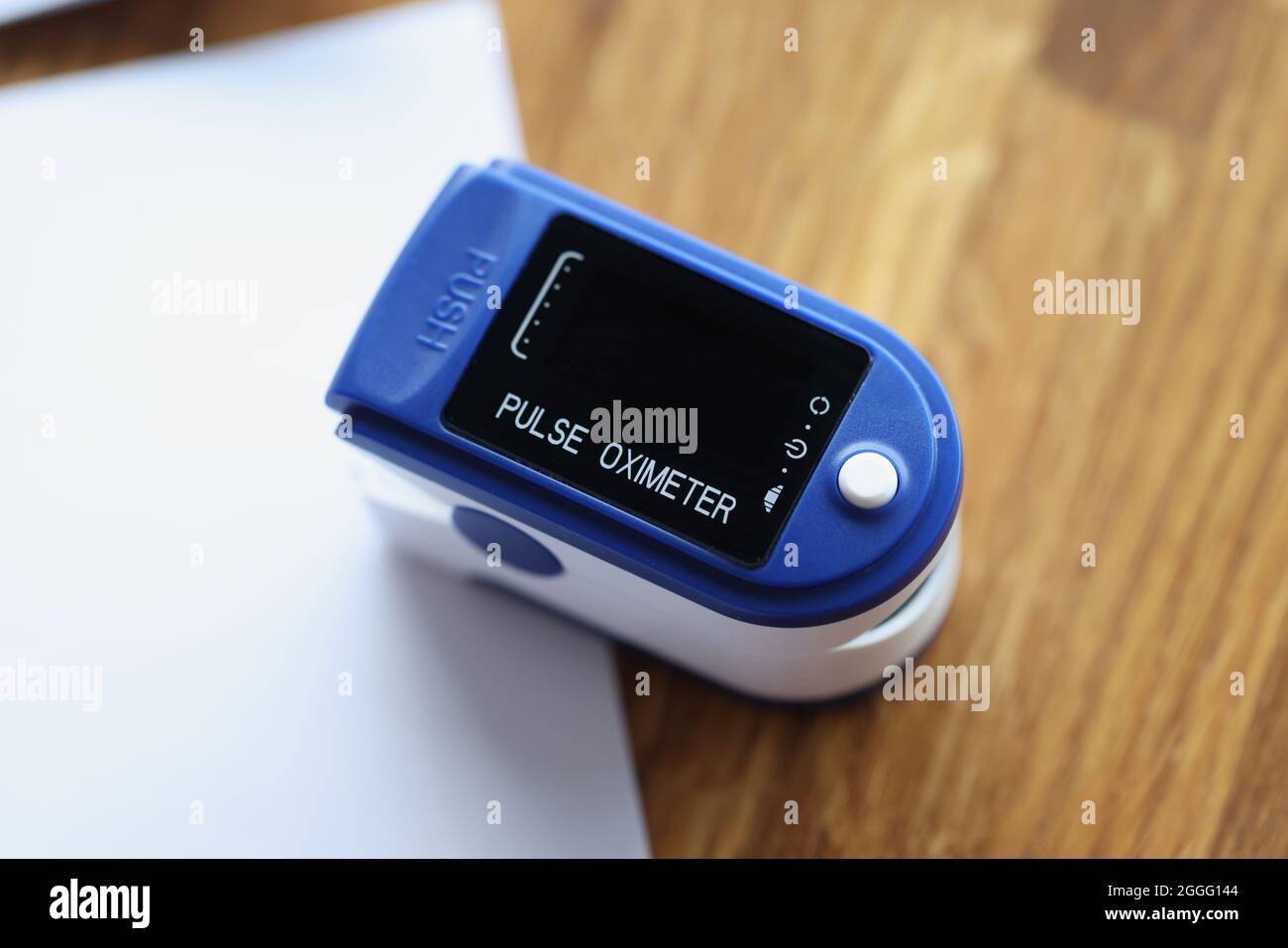Blue pulse oximeter lying on wooden table with documents closeup Stock ...