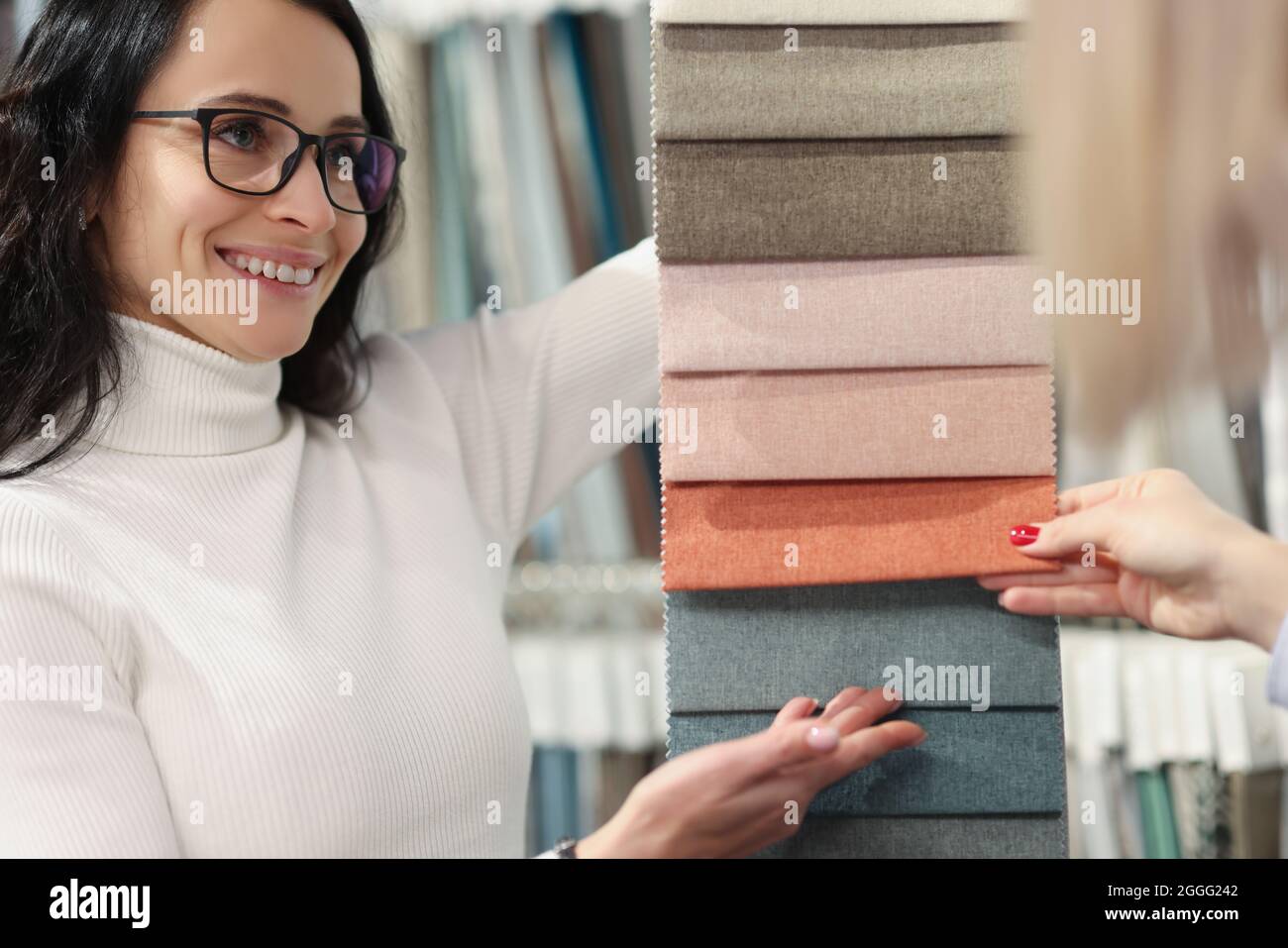 Woman salesman showing customer samples of fabrics in store Stock Photo ...