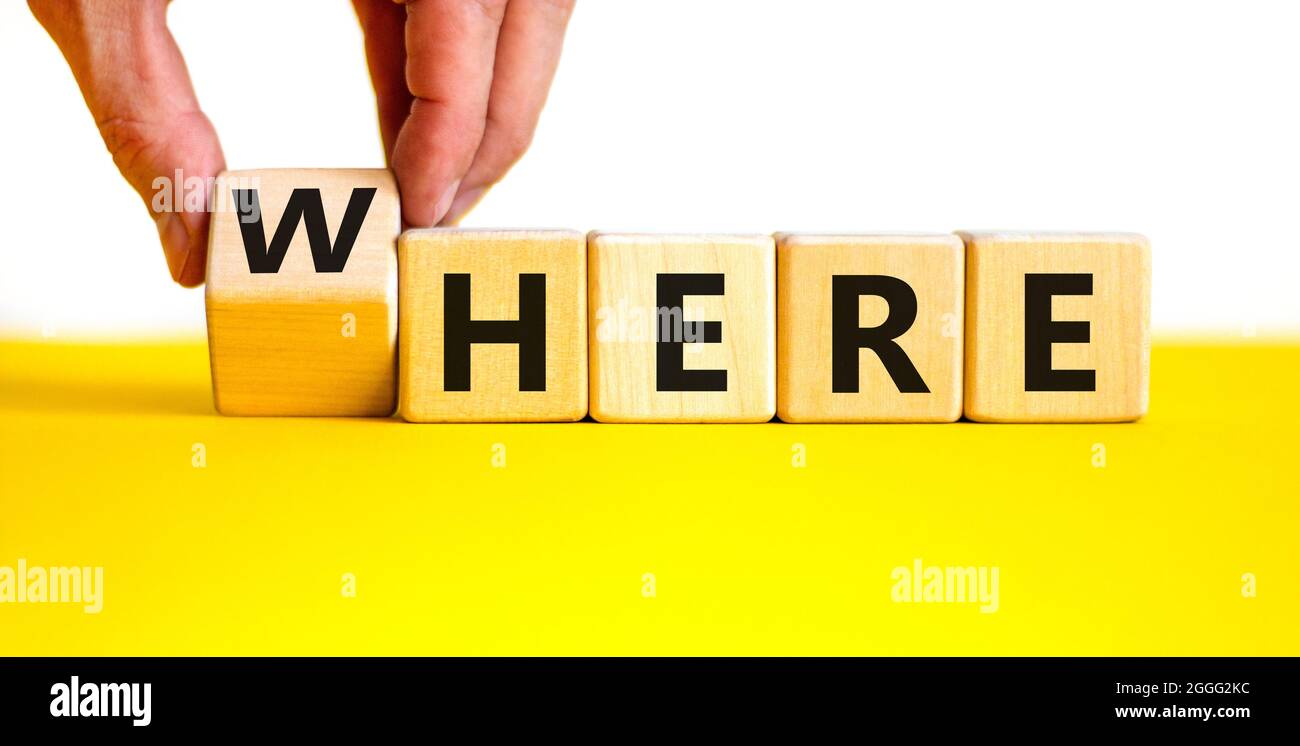 Where or here symbol. Businessman turns a wooden cube, changes the word ...