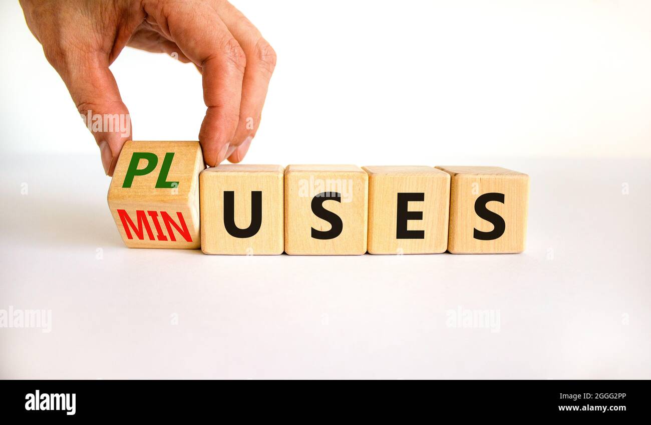 Pluses and minuses symbol. Businessman turns a wooden cube and changes ...