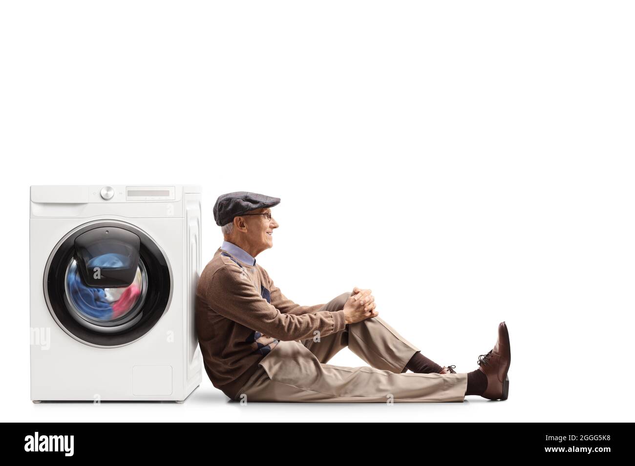 Elderly man sitting on the gorund and leaning on a washing machine ...
